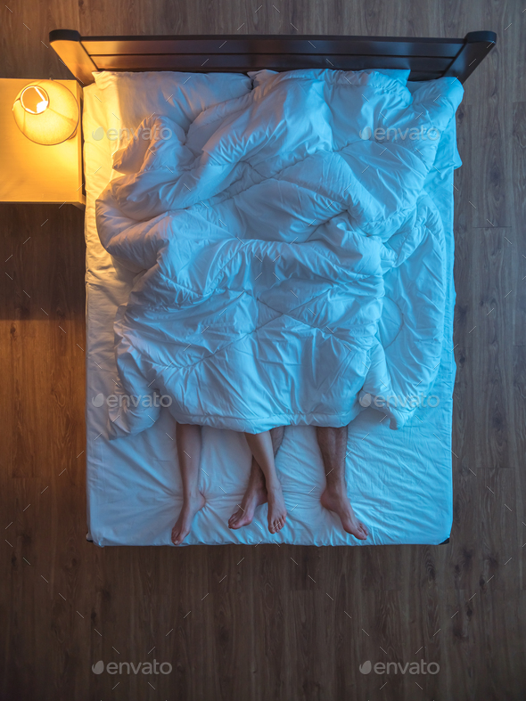 The couple lay under cover on the bed. evening night time. view from ...