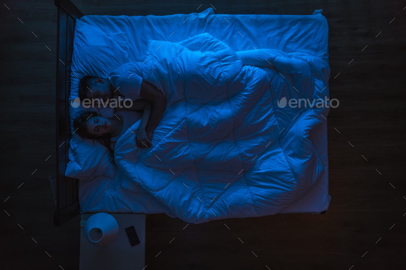 The couple sleeping on a bed. Evening night time. View from above ...