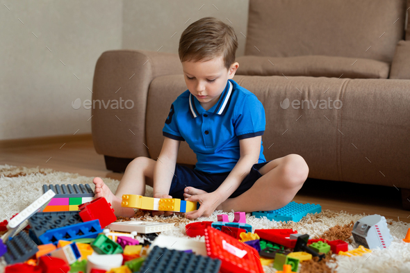Little boy playing construction kit on the floor Stock Photo by StudioPeace