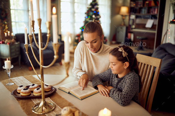 Jewish mother and daughter reading Tanakh during Hanukkah at home ...
