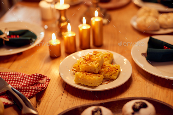 Jewish noodle casserole with candlelight on dining table on Hanukkah ...