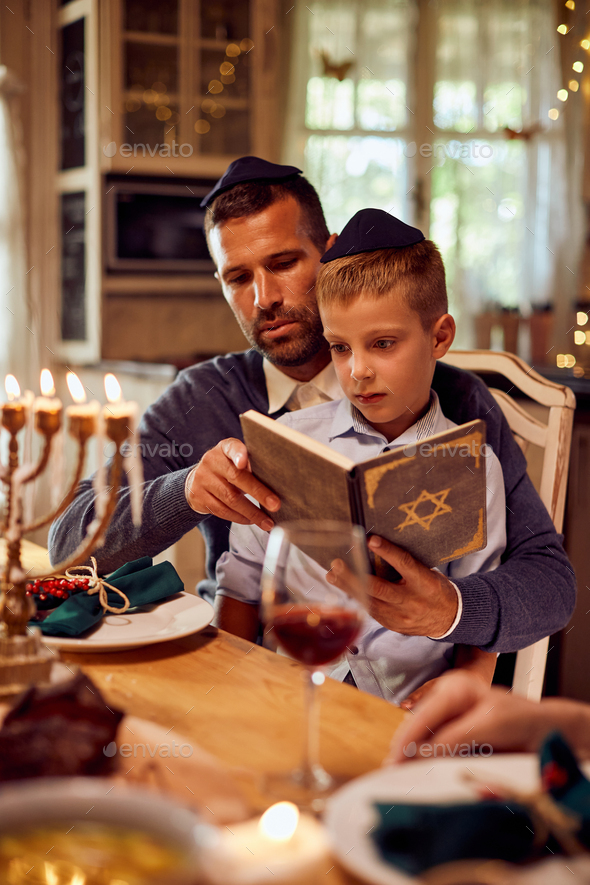 Jewish father and son reading Tanakh at dining table on Hanukkah. Stock ...