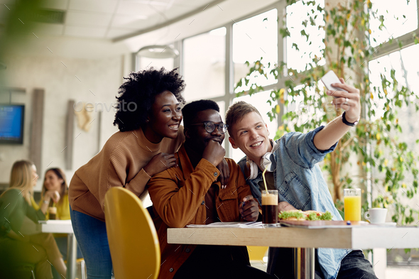 Happy students taking selfie on lunch break in cafeteria. Stock Photo ...