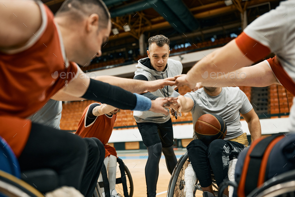 Wheelchair basketball team and their coach gathering hands in unity ...