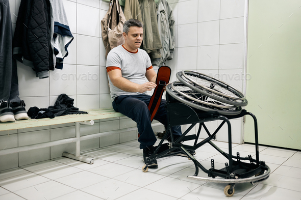 Disabled athletic man adjusting his wheelchair in locker room. Stock ...