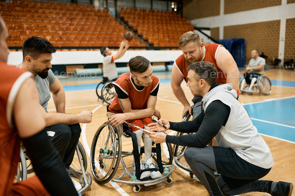 Disabled basketball team and their coach analyzing game strategy during ...