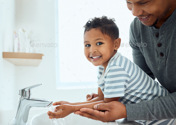Shot of an adorable little boy washing his hands with the help of his ...