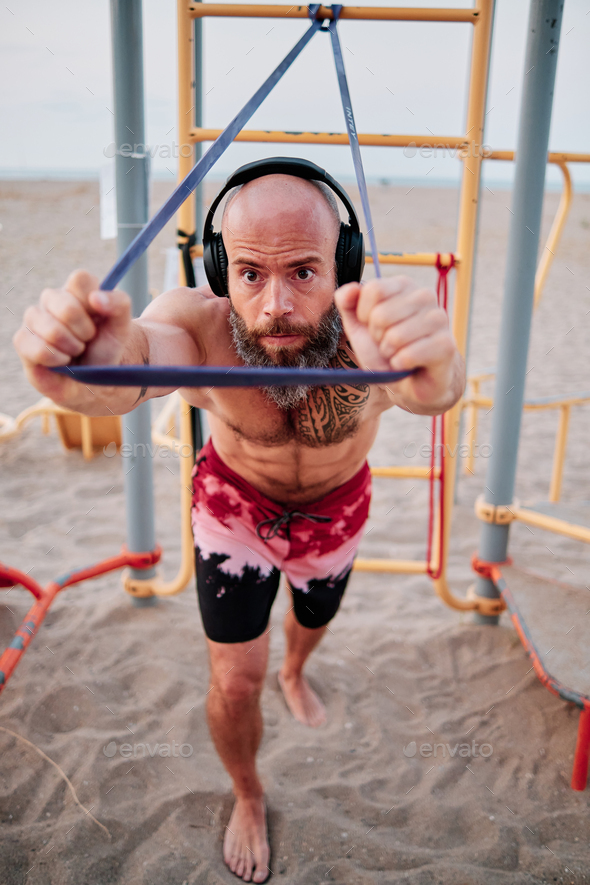 Fitness man doing calisthenics workout with a resistance rubber band ...