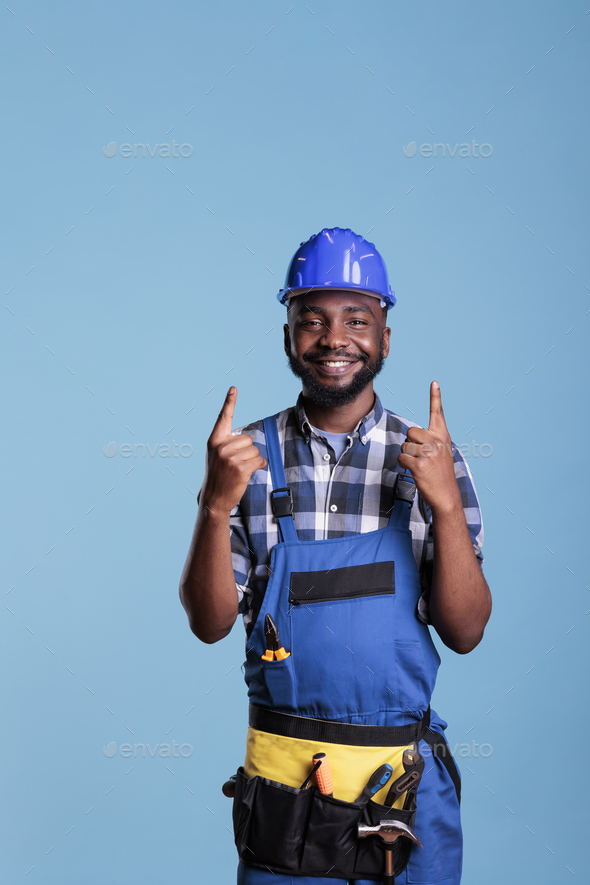 Happy builder pointing upward with both hands Stock Photo by DC_Studio