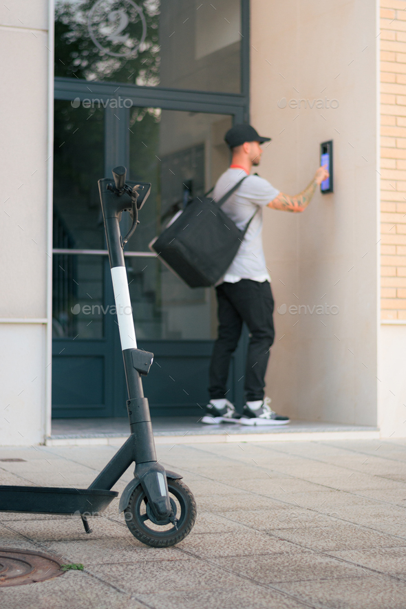 Delivery man delivering a package with an electric scooter Stock Photo ...