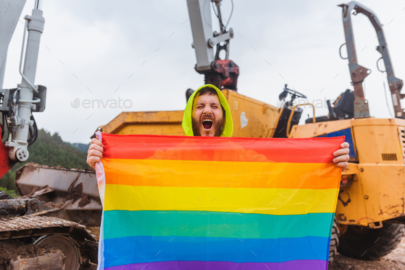 worker man on a construction site shouts while holding a rainbow lgbt ...