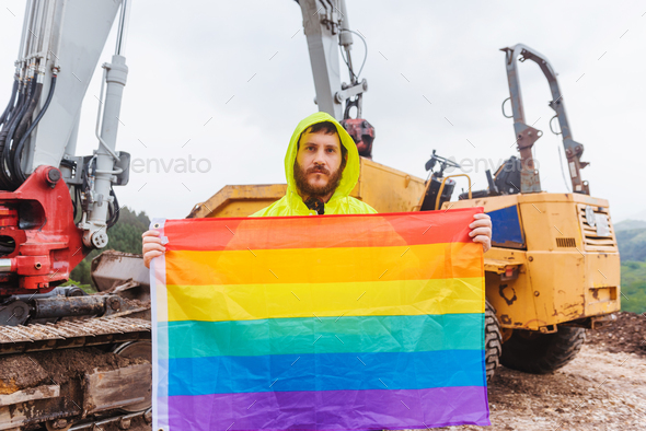 working man on a construction site holding a rainbow lgbt pride flag ...