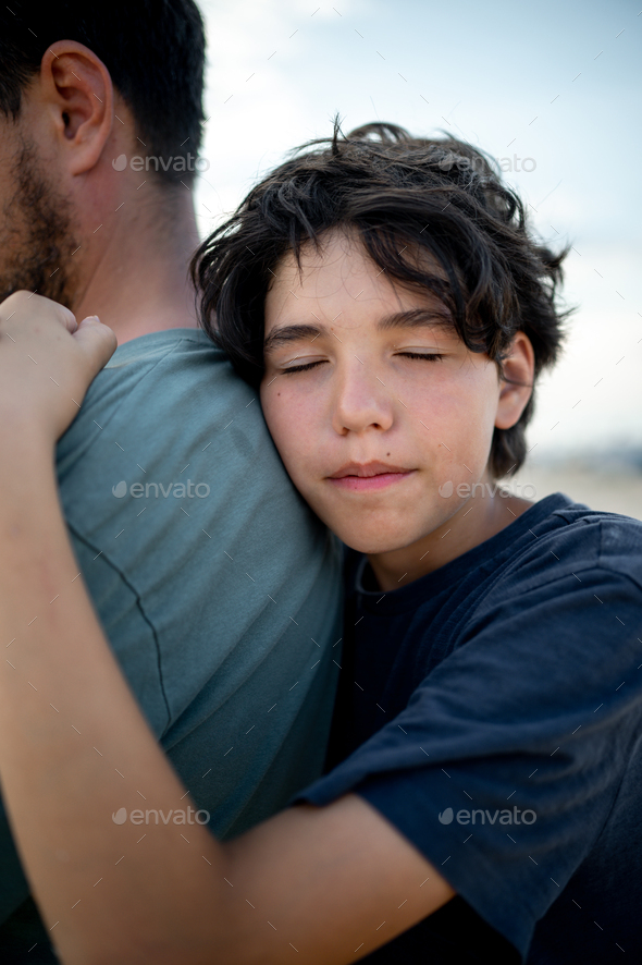 The teenage boy snuggles with tenderness to the strong shoulder of the ...