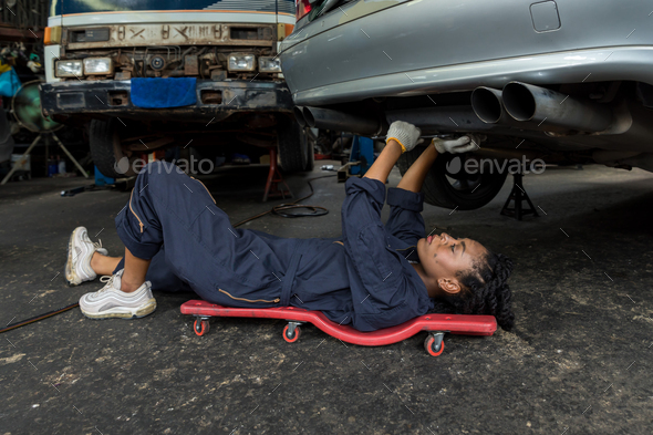 Mechanic lying down and working under car at auto service garage. Stock ...