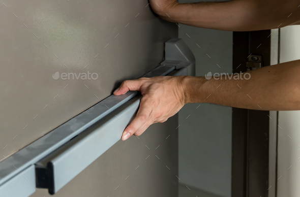 Hand is Opening the emergency fire exit door. Emergency fire exit door ...