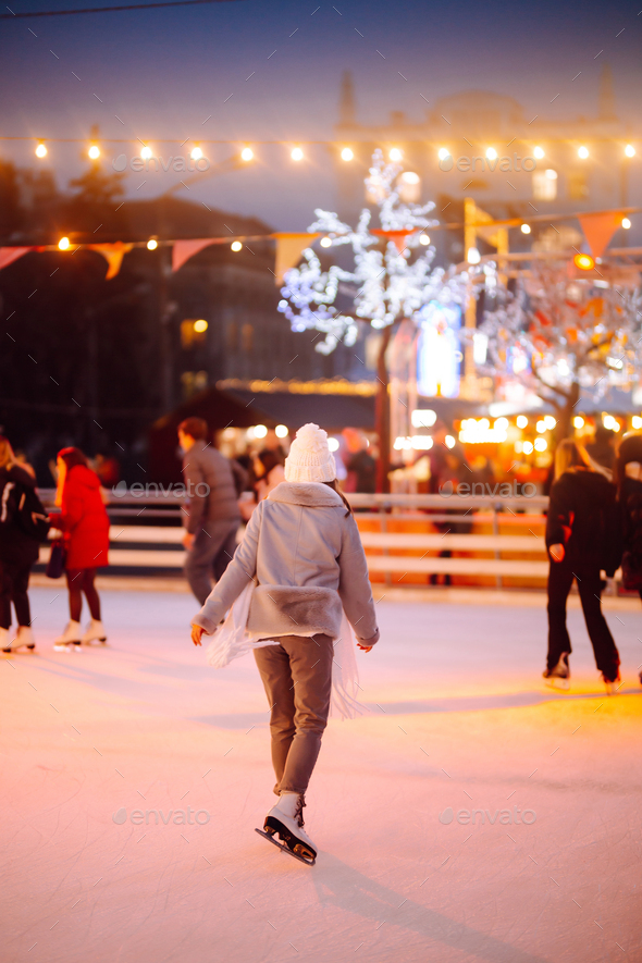 Woman ice skating on the ice arena in the city square in winter on ...