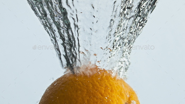 Fresh orange splashing water in light background closeup. Tropical ...