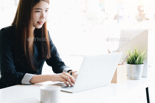 Beautiful young Asian girl working at modern office with a laptop ...