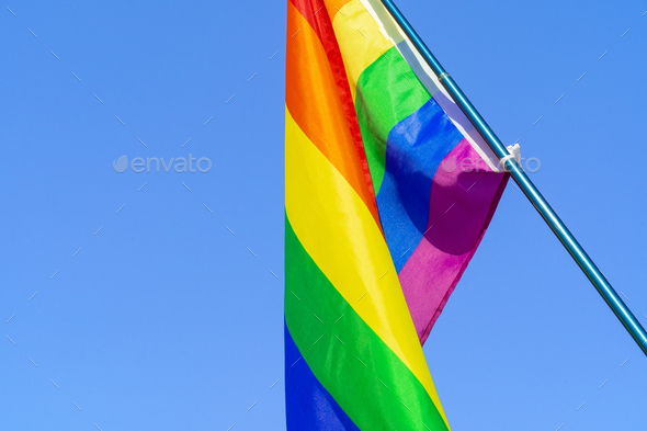 LGBT waving flag in the sky on flagpole Stock Photo by FabrikaPhoto