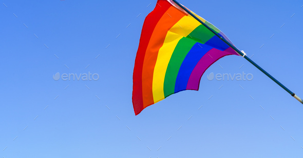 LGBT waving flag in the sky on flagpole Stock Photo by FabrikaPhoto
