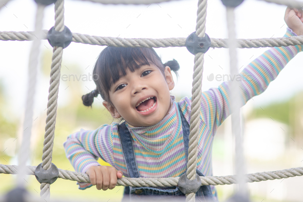 Cute children. Asian girl climbing in a rope playground structure at ...
