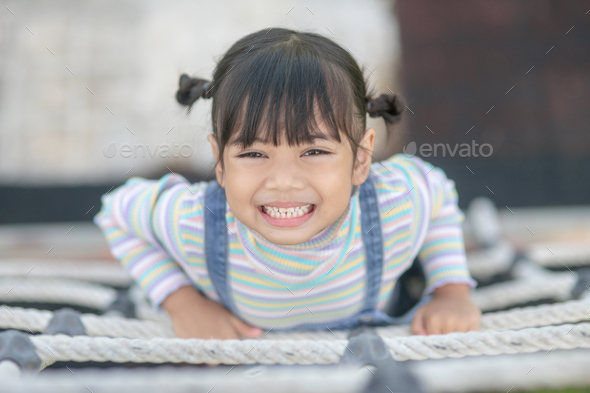 Cute children. Asian girl climbing in a rope playground structure at ...