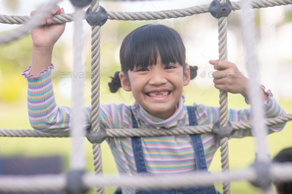 Cute children. Asian girl climbing in a rope playground structure at ...