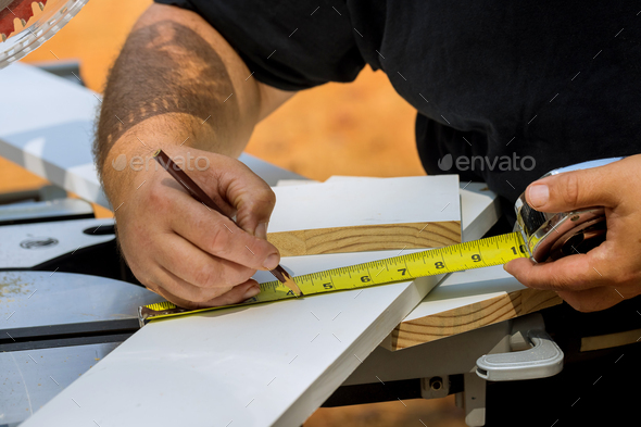 A man measures a piece of wood with tape measure Stock Photo by photovs