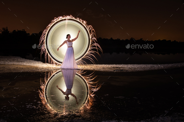 Woman posing for light painting with bright lights in the dark ...