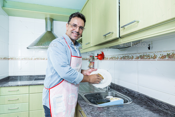 Adult male washing dishes in the kitchen at home Stock Photo by Juan_Algar