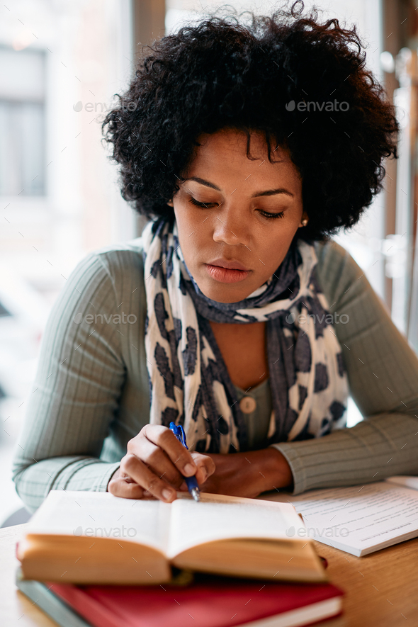 Mid adult black woman studying from books in a library. Stock Photo by ...
