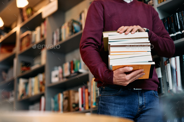 Unrecognizable man carrying stack of books in a library. Stock Photo by ...