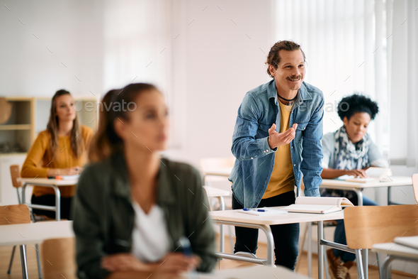 Happy male student talking while attending a lecture in the classroom ...