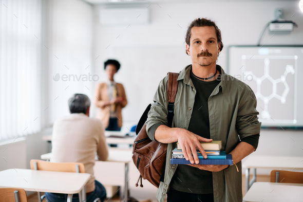 Portrait of mid adult male student standing in the classroom and ...