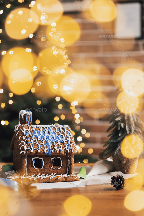 Gingerbread house on Christmas table with decorations, candles in ...