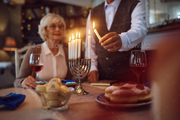 Close up of senior man celebrating Hanukkah with his wife and lighting ...