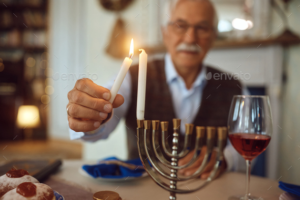 Close up of senior man lights candles in menorah during Jewish festival ...