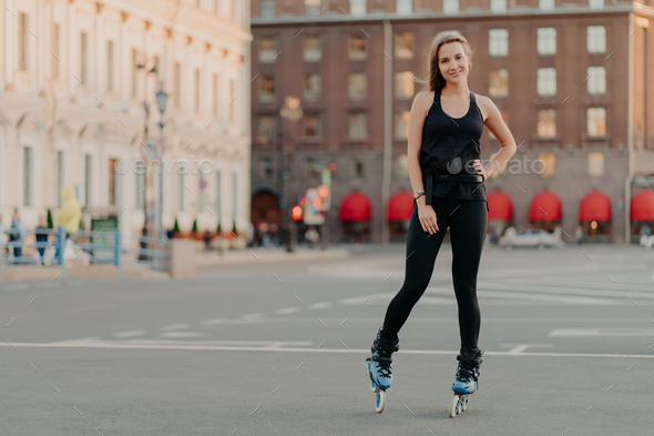 Horizontal shot of active woman practices rollerblading poses Stock ...