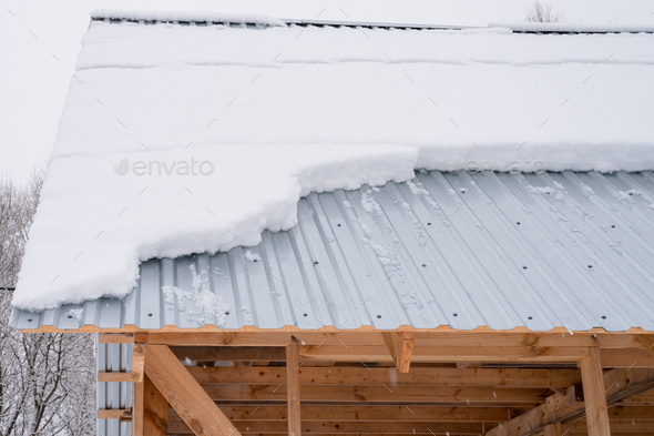 snow sliding down from roof. building construction house with metal ...