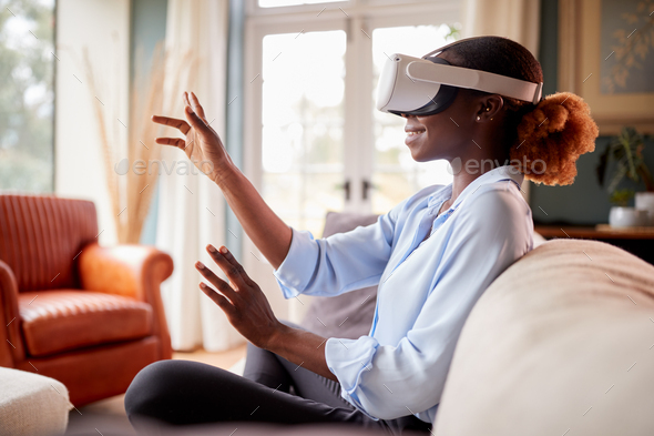 Woman Relaxing On Sofa At Home Wearing VR Headset And Interacting With ...