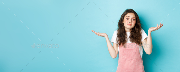 Portrait of confused cute brunette girl shrugging shoulders, know ...