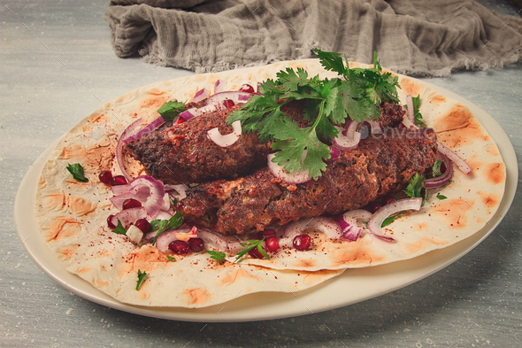 Lula kebab, on lavash, with red onion, pomegranate, and sumac, top view ...