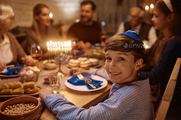 HAppy Jewish boy having family dinner at dining table on Hanukkah and ...