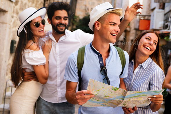 Smiling gorup of friends with map. Tourism, travel, leisure, holidays ...