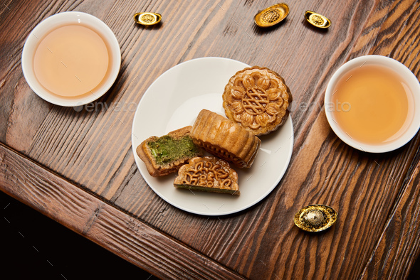 traditional mooncakes with tea cups and gold ingots on wooden table ...