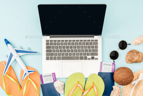 top view of laptop with blank screen, flip flops, passports with air ...