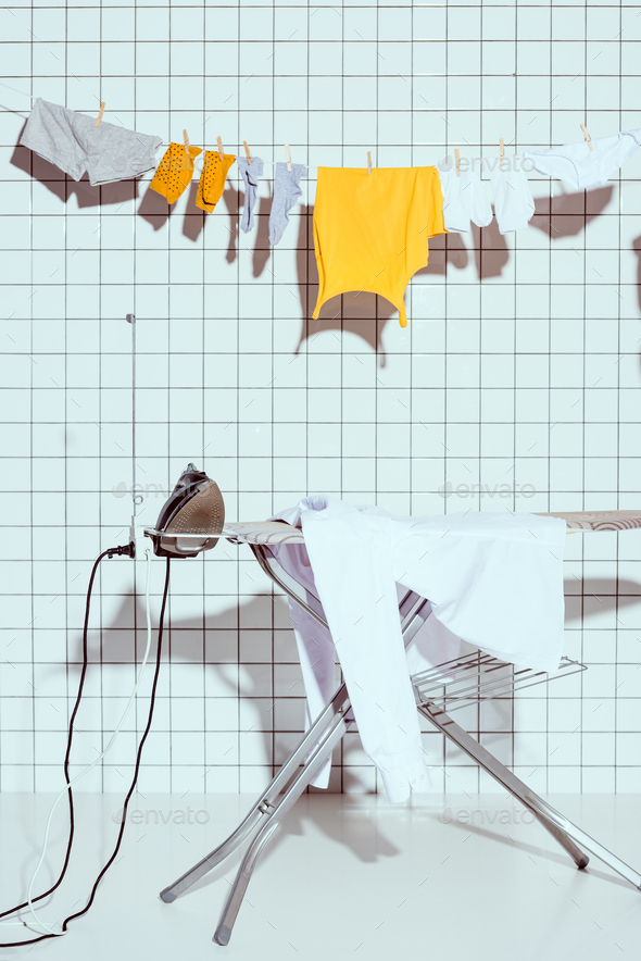 hanging clothes and ironing board with white tile on background in ...