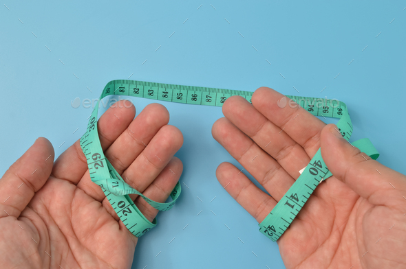 Hand holding tape measure isolated on a blue background Stock Photo by ...