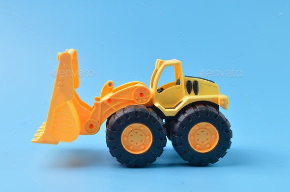 Construction plastic backhoe tractor toy isolated on a blue background ...