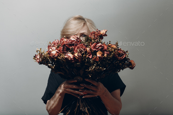Upset elderly woman hold withered dry old rose flowers bouquet. Stock ...